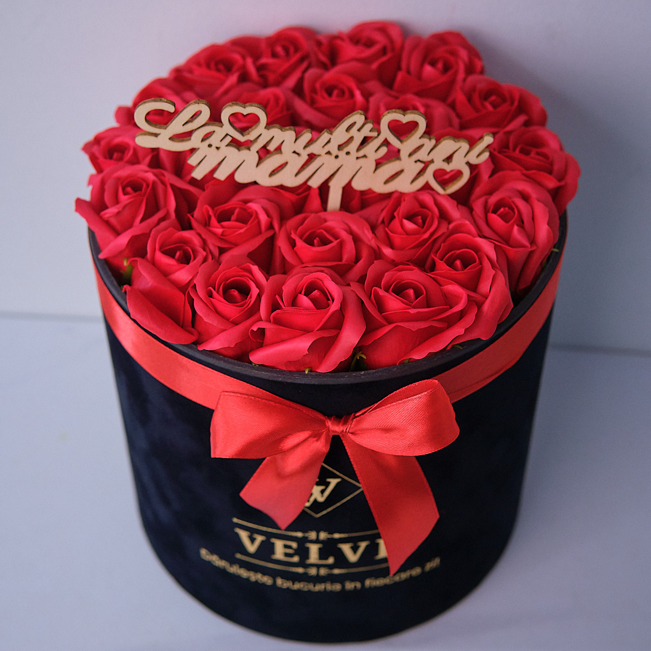 Aranjament floral in cutie rotunda neagra, cu 25 trandafiri rosii din sapun si mesaj "La multi ...