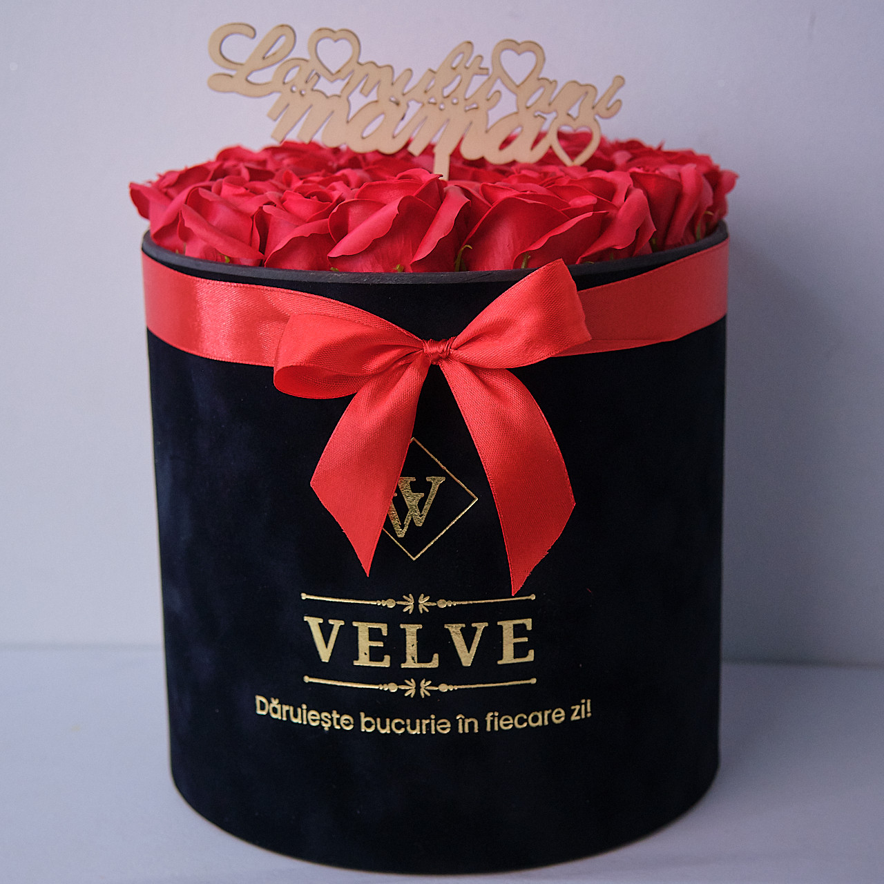 Aranjament floral in cutie rotunda neagra, cu 25 trandafiri rosii din sapun si mesaj "La multi ...